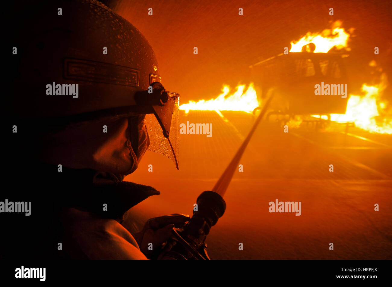 Naval fire fighter in training, with blazing helicopter mockup. A jet ...
