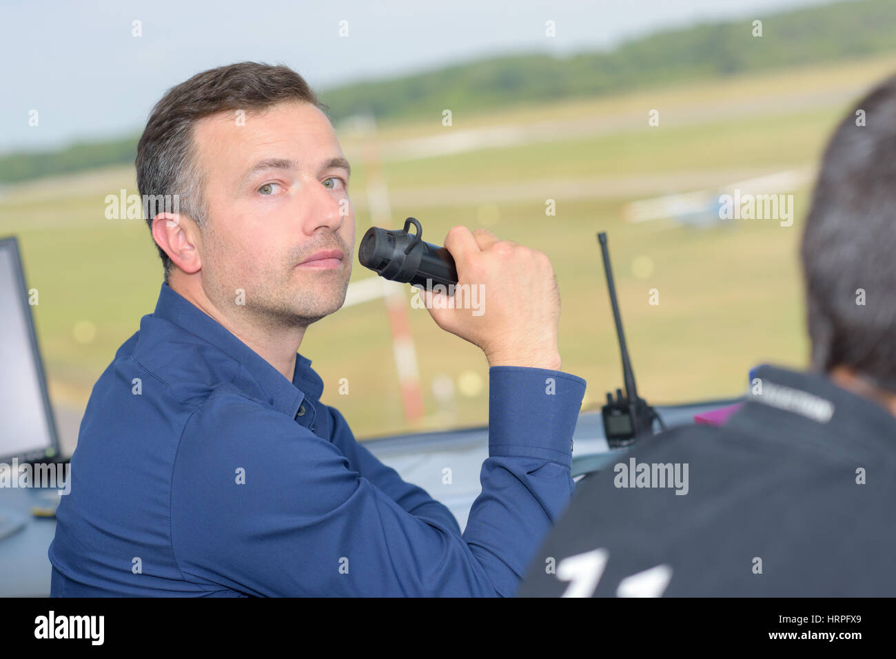 Man in control tower talking into radio receiver Stock Photo - Alamy