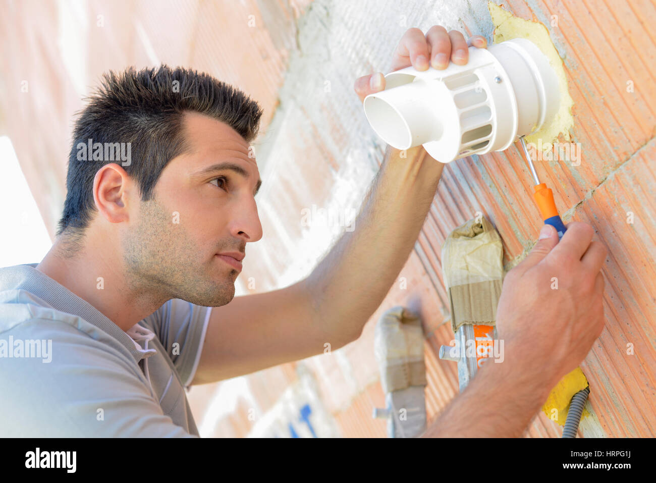 Mason installing an outdoor air vent Stock Photo - Alamy