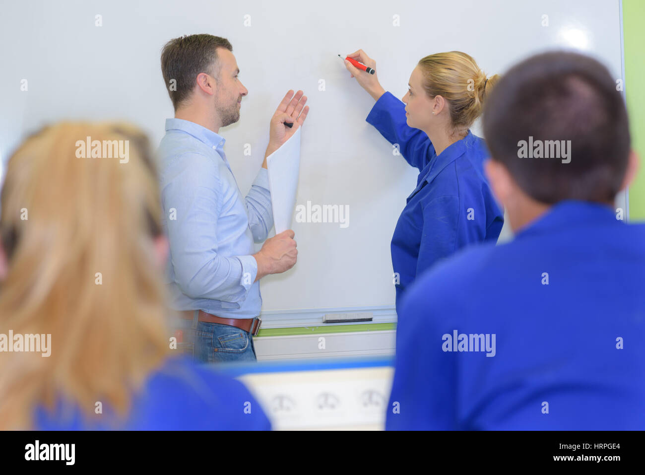 Student at board with teacher, writing Stock Photo - Alamy