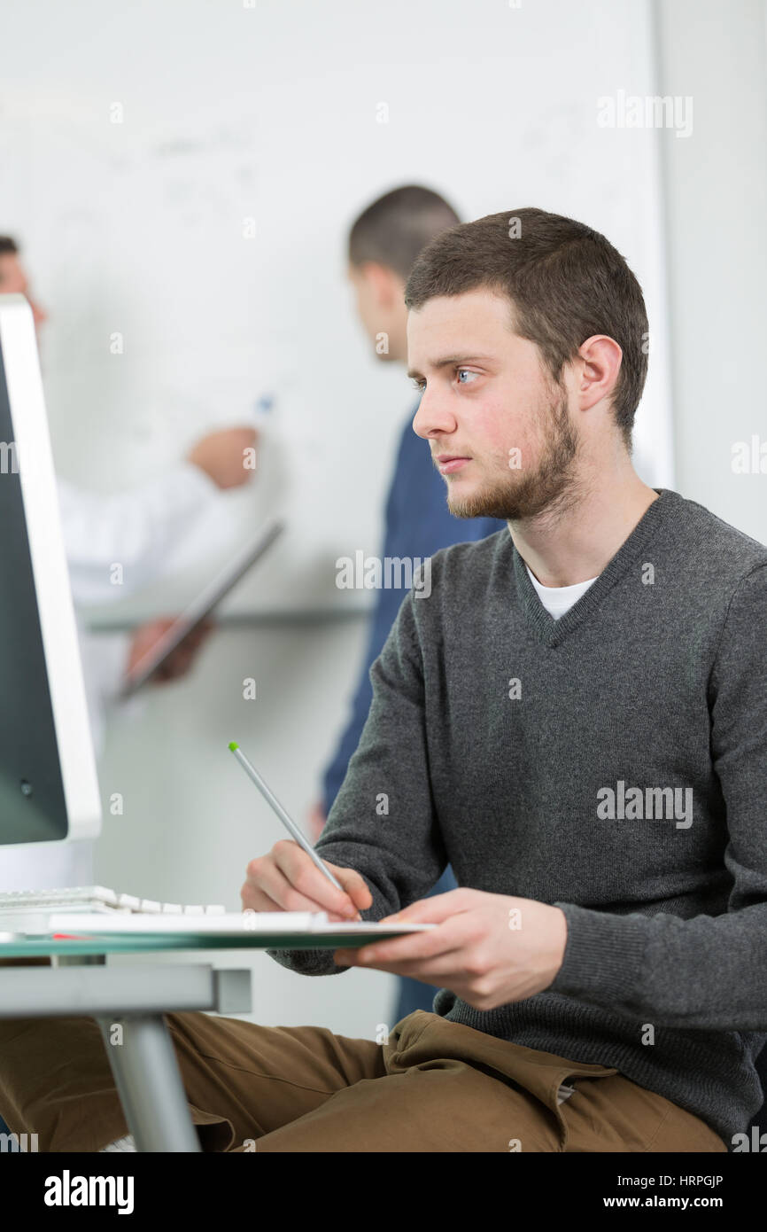 Young man taking notes form computer Stock Photo - Alamy