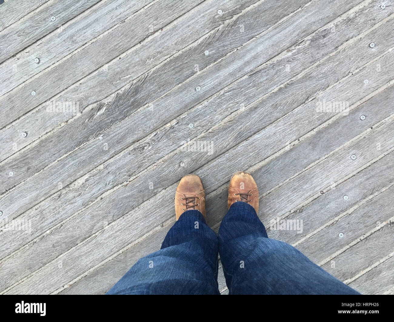 Point of view (POV) looking down at feet, standing on a wooden ...