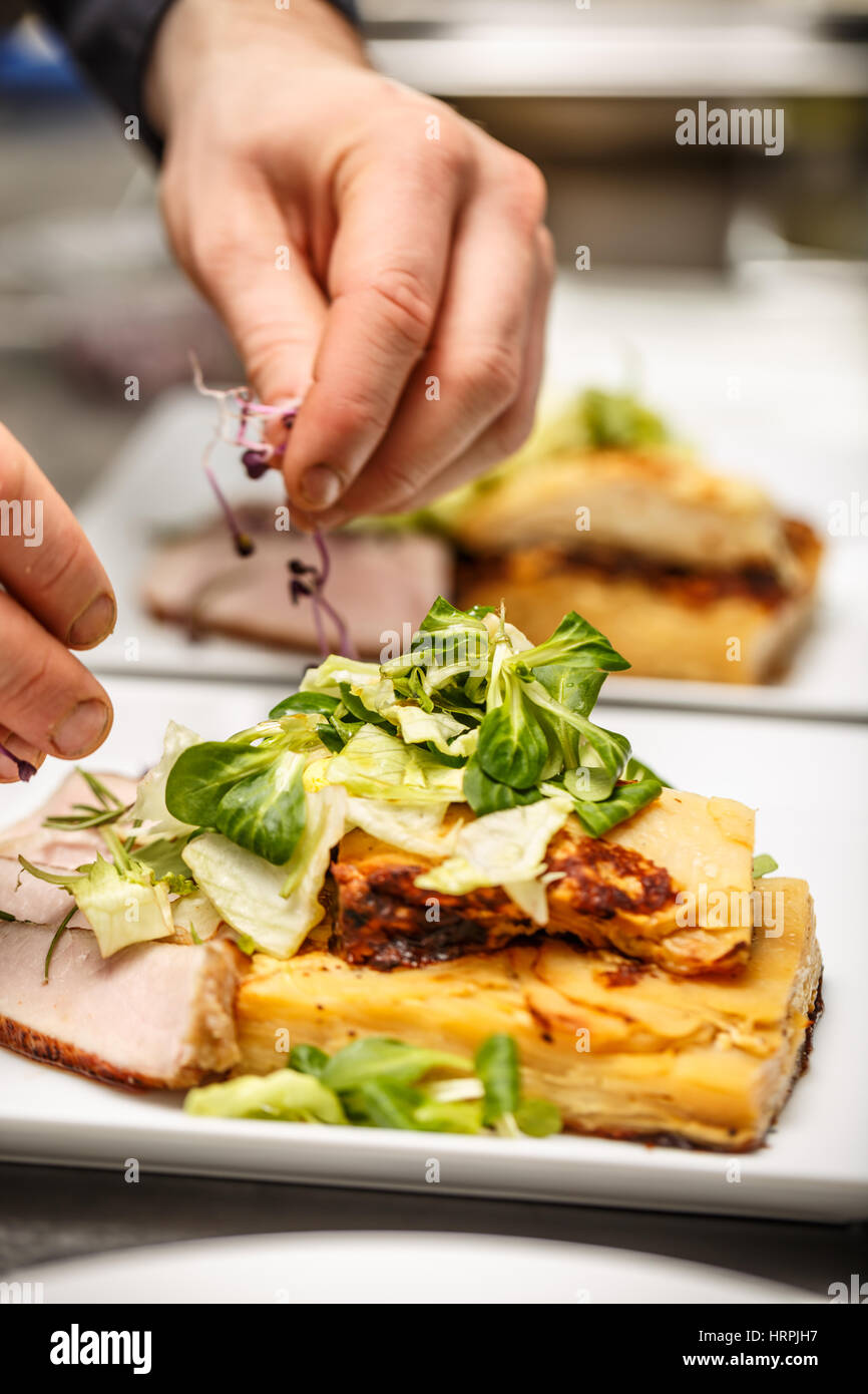 Chef adding finishing touch on his dish before it goes on the table ...