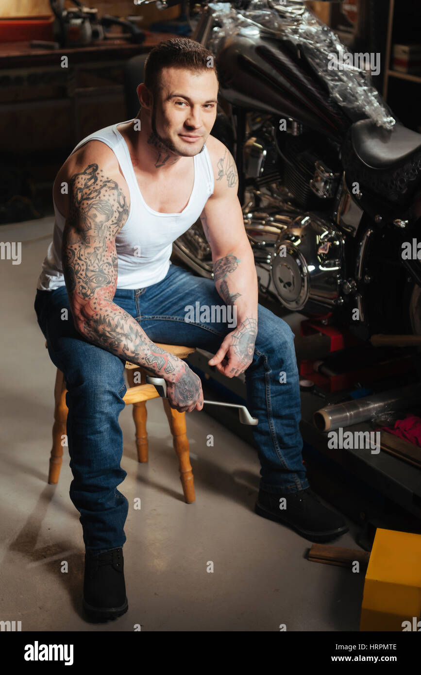 Happy to be here. Sporty smiling motorcyclist wearing white T-shirt ...