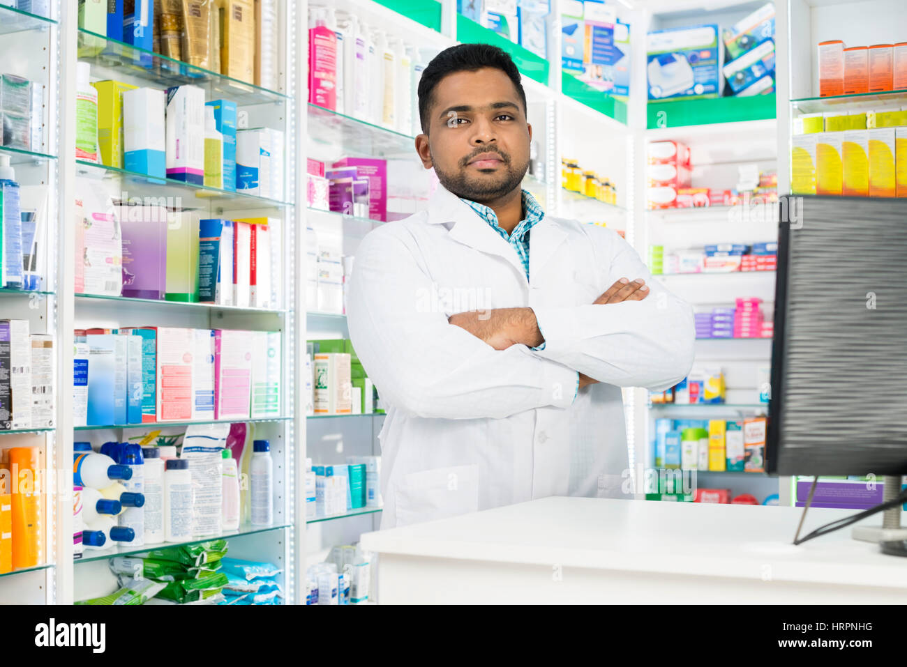 Portrait of confident young chemist in labcoat standing arms crossed at ...