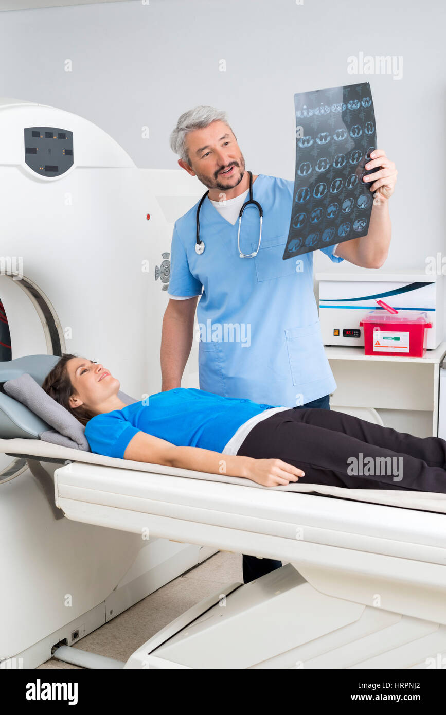 Male doctor explaining chest X-ray to female patient lying on MRI ...