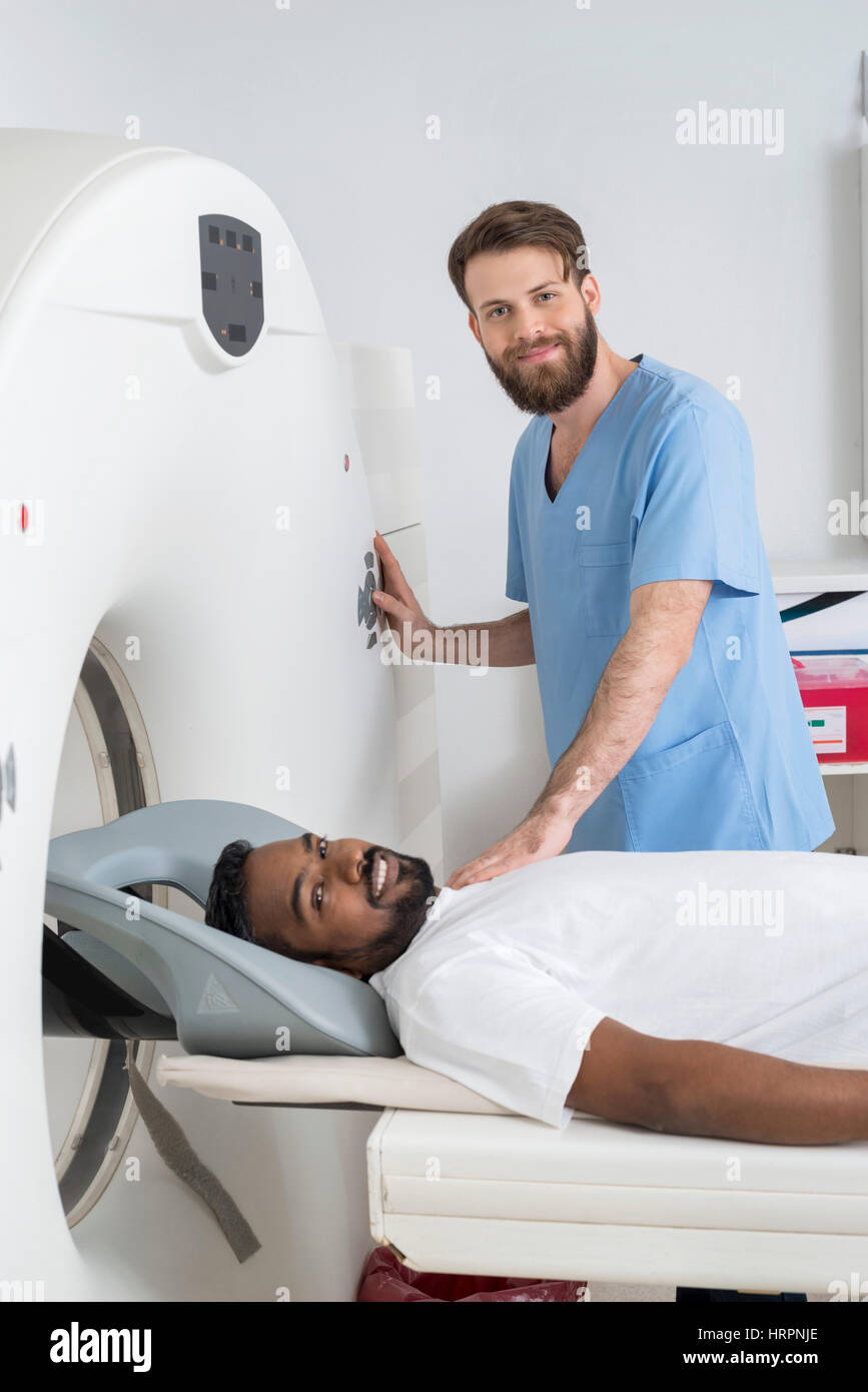 Portrait of young doctor about to start CT scan on male patient in ...
