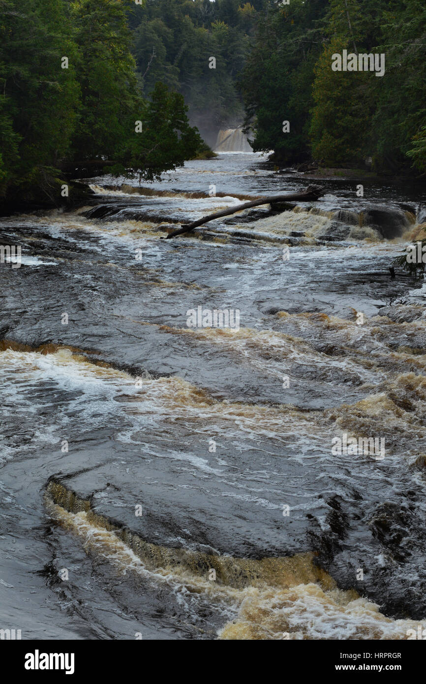 Looking down a rushing river with a waterfall amid the trees in the ...