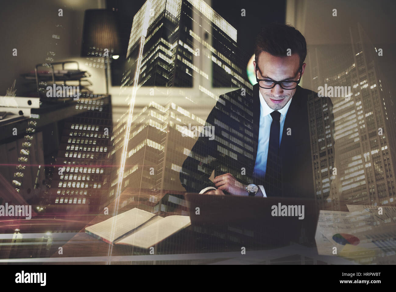 Optimistic businessman working on laptop at office in the night ...