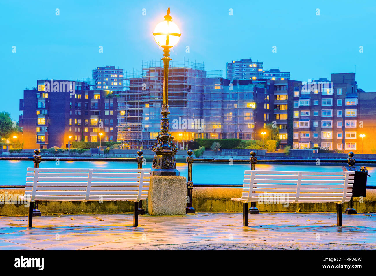Riverside benches at night with out of focus buildings in the distance ...