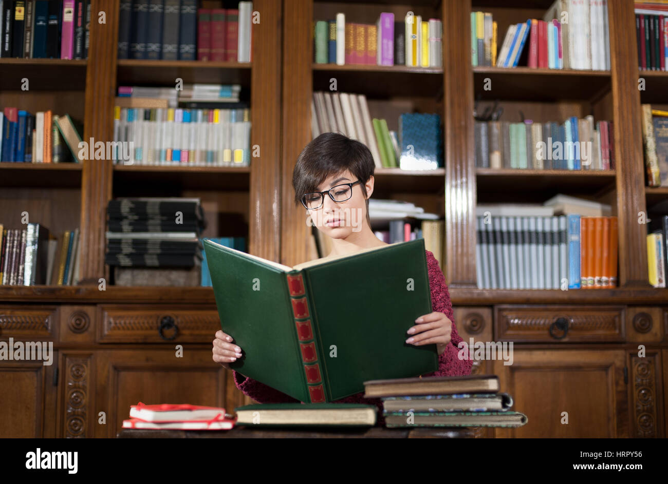 Young female student with absorbed face expression while reading book ...