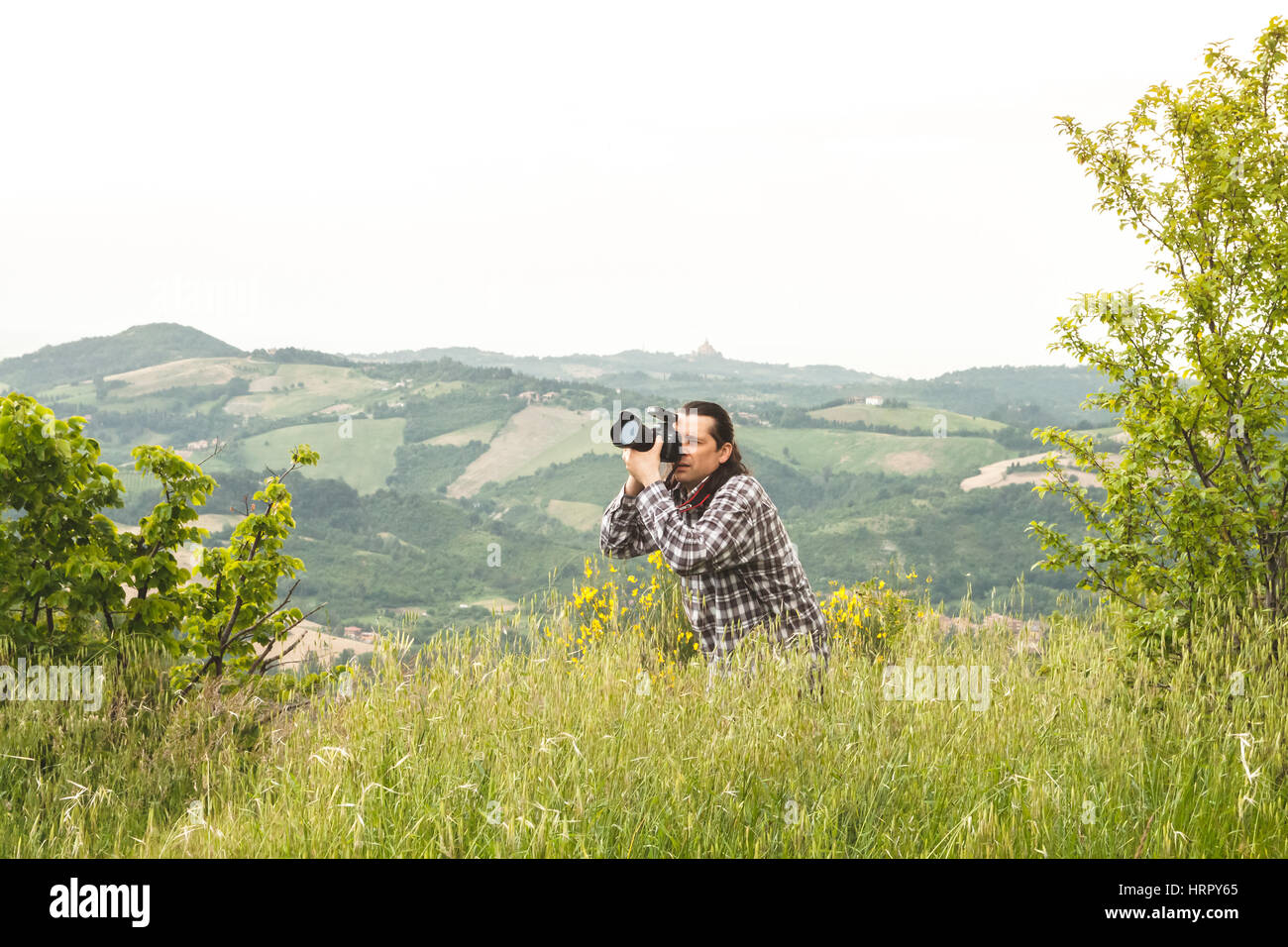 Man photographer on the field with camera photo ready to take a picture ...