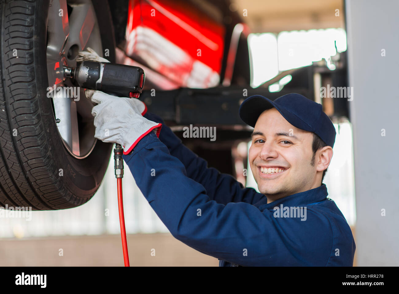 Portrait of a mechanic replacing a wheel Stock Photo - Alamy