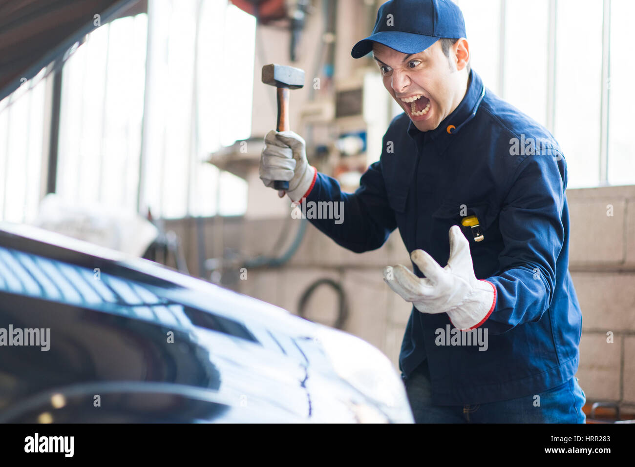 Angry mechanic holding a hammer Stock Photo - Alamy