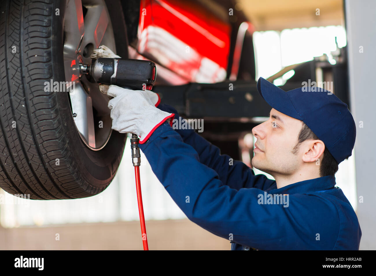 Mechanician changing car wheel in auto repair shop Stock Photo - Alamy