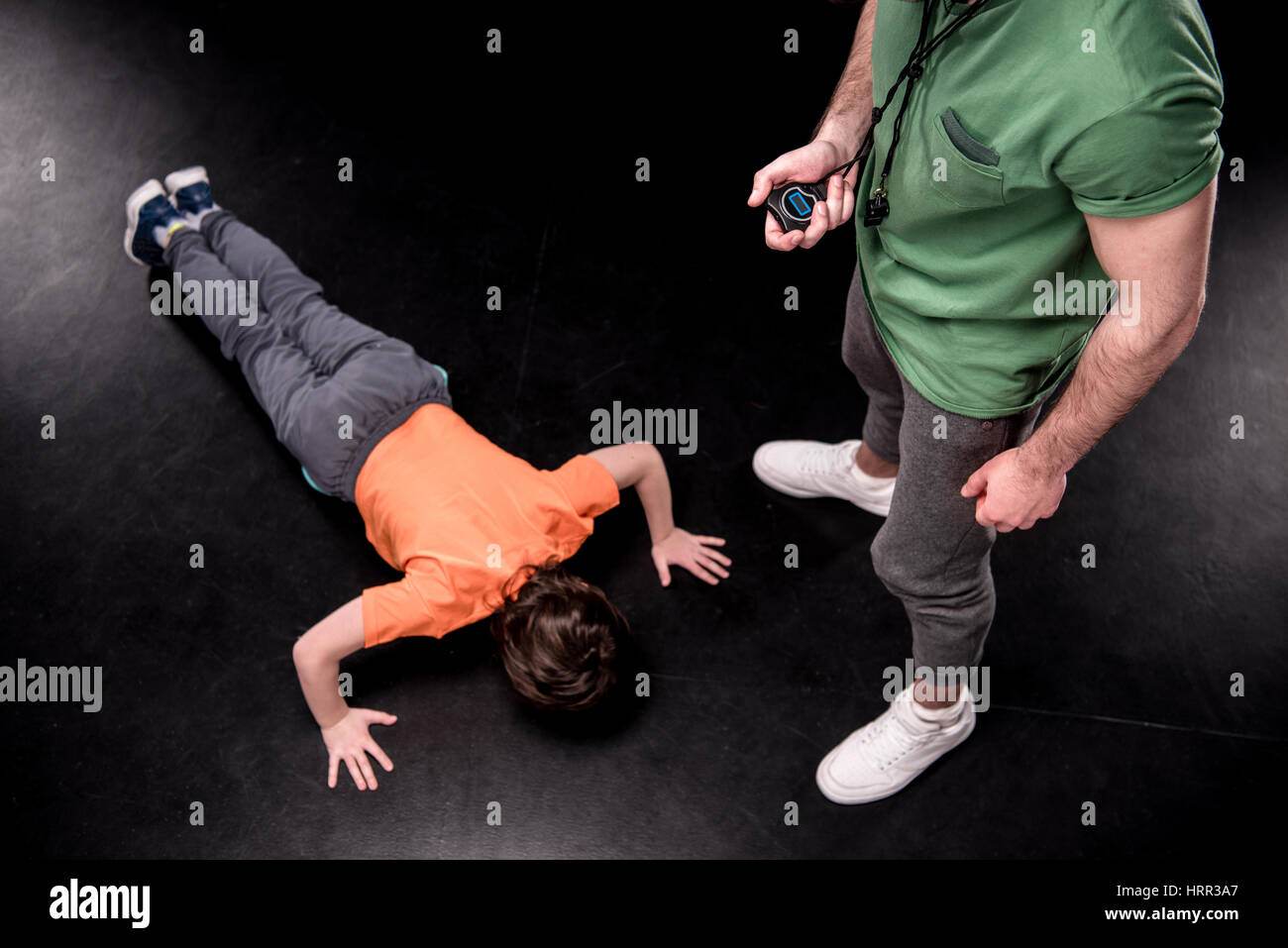 high angle view of man controlling time while boy doing push up on ...