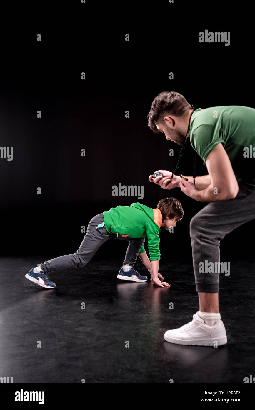 side view of man controlling time while boy training on black Stock ...