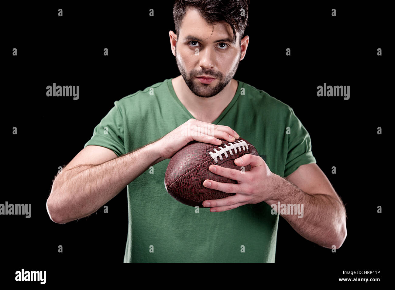 portrait of confident man with rugby ball looking away on black Stock ...