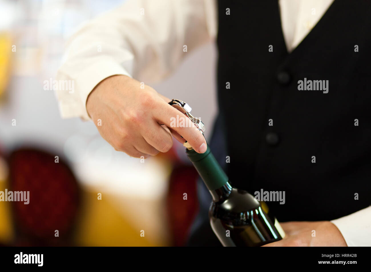 Waiter uncorking a wine bottle in a restaurant Stock Photo - Alamy