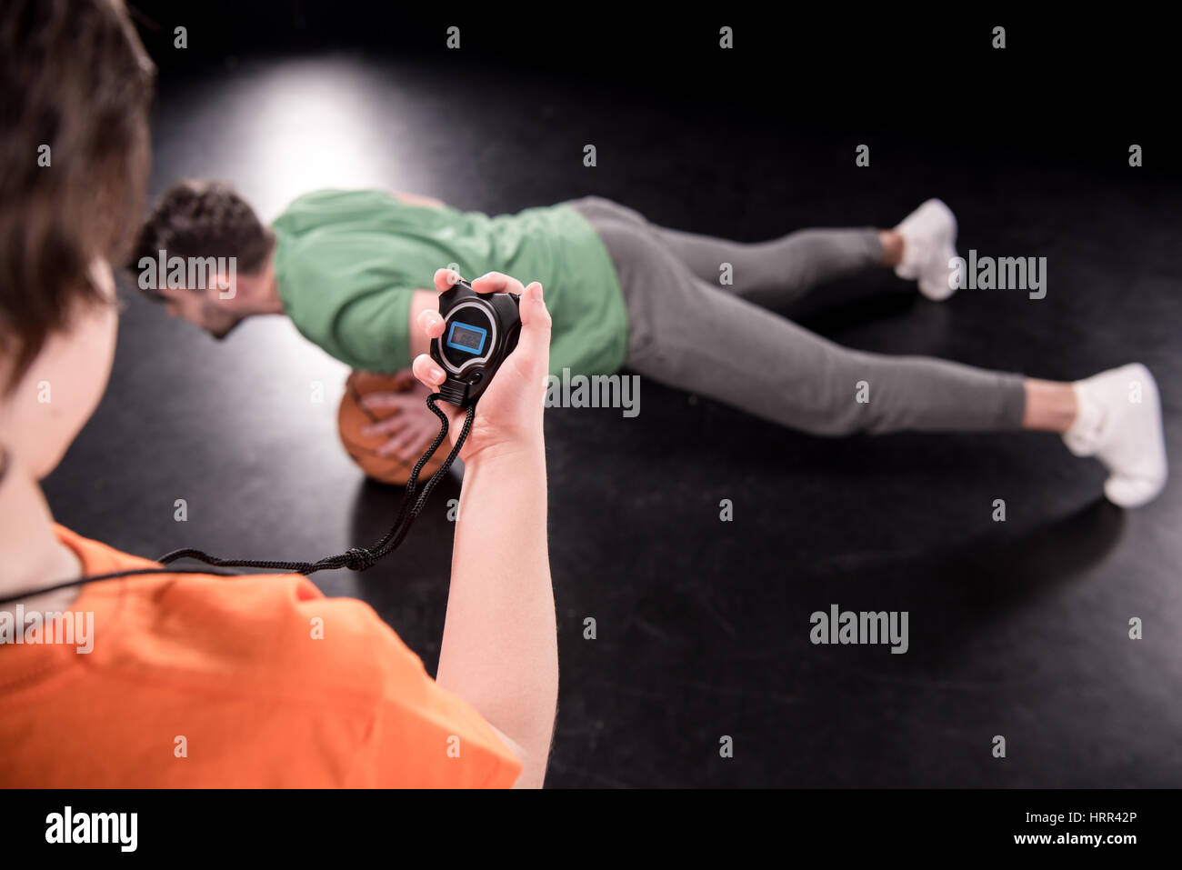 back view of boy with stopwatch controlling time while man doing push ...