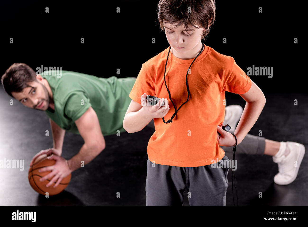 concentrated boy with stopwatch controlling time while man training ...