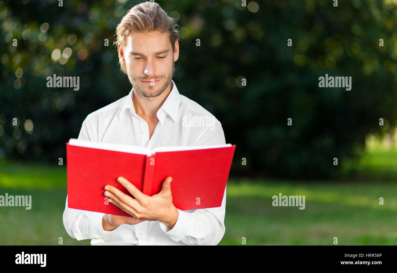Young man reading a book outdoor Stock Photo - Alamy