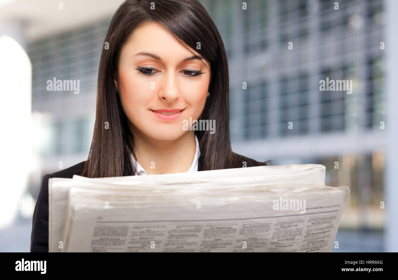 Beautiful woman reading the newspaper outdoor Stock Photo - Alamy