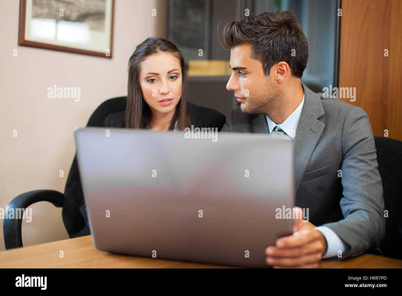 Smiling business people using a laptop computer in their office Stock ...