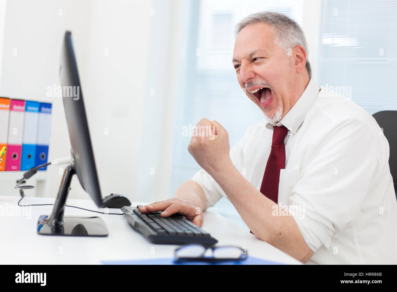Very happy businessman looking at his computer monitor Stock Photo - Alamy