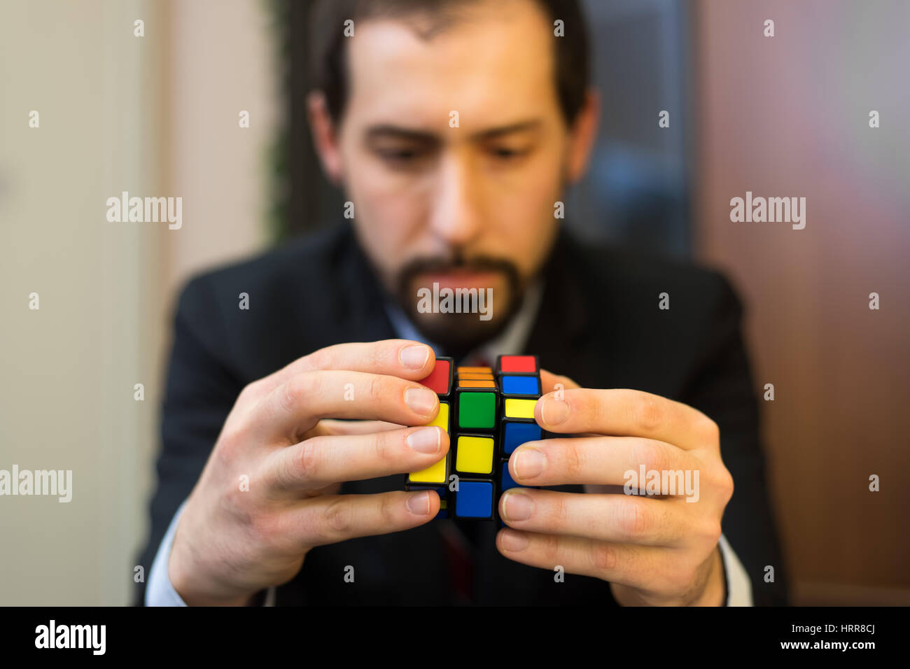 Puzzled businessman trying to solve a puzzel cube Stock Photo - Alamy