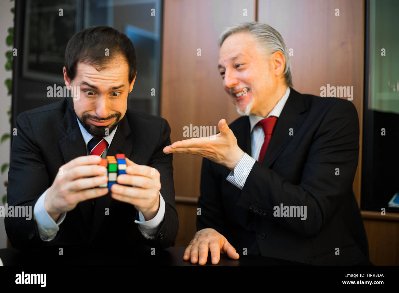 Businessman trying to solve rubik cube Stock Photo - Alamy