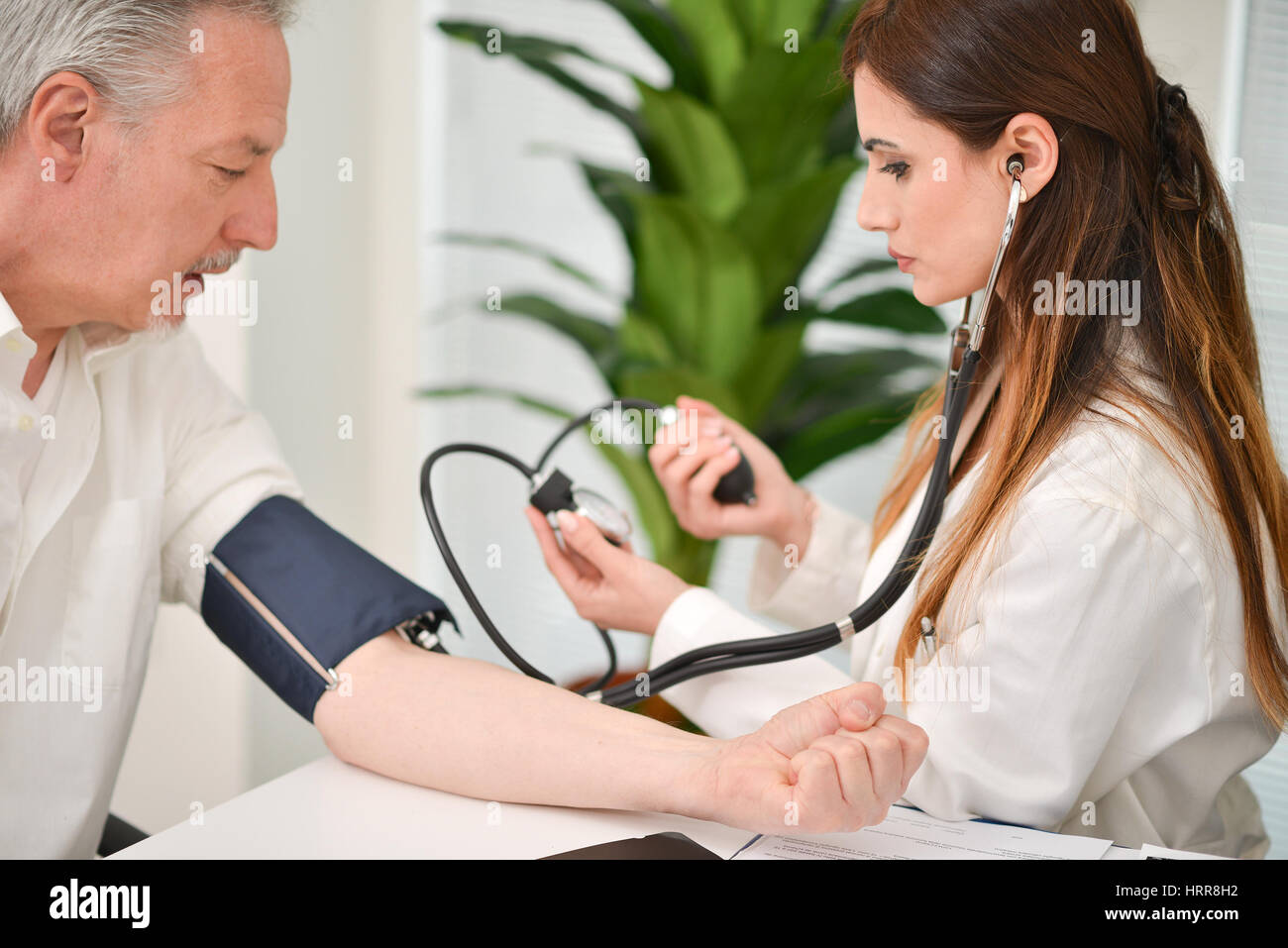 Doctor using a stethoscope and a sphygmomanometer to check blood ...