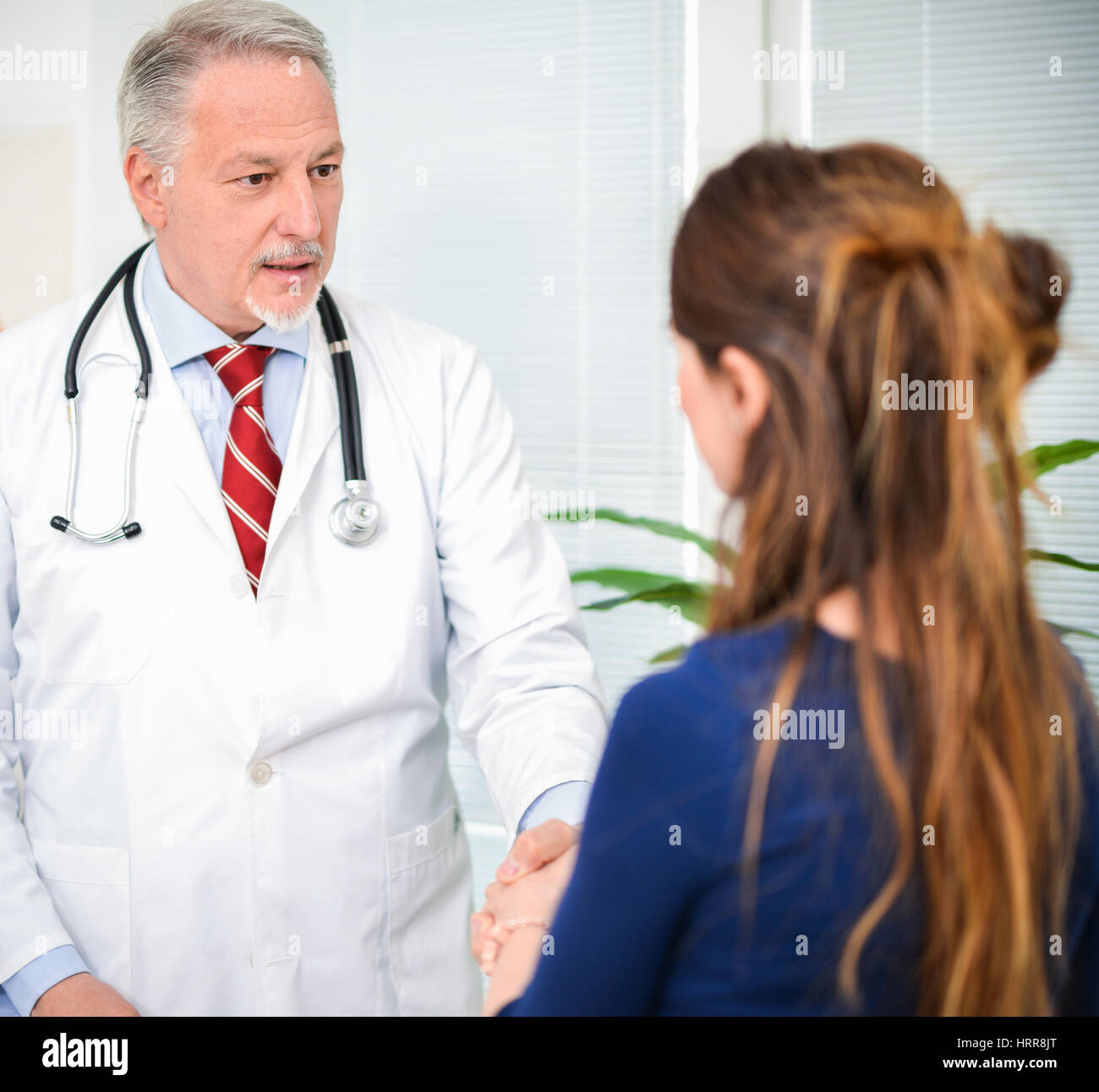 Doctor giving an handshake to a patient in his studio Stock Photo - Alamy