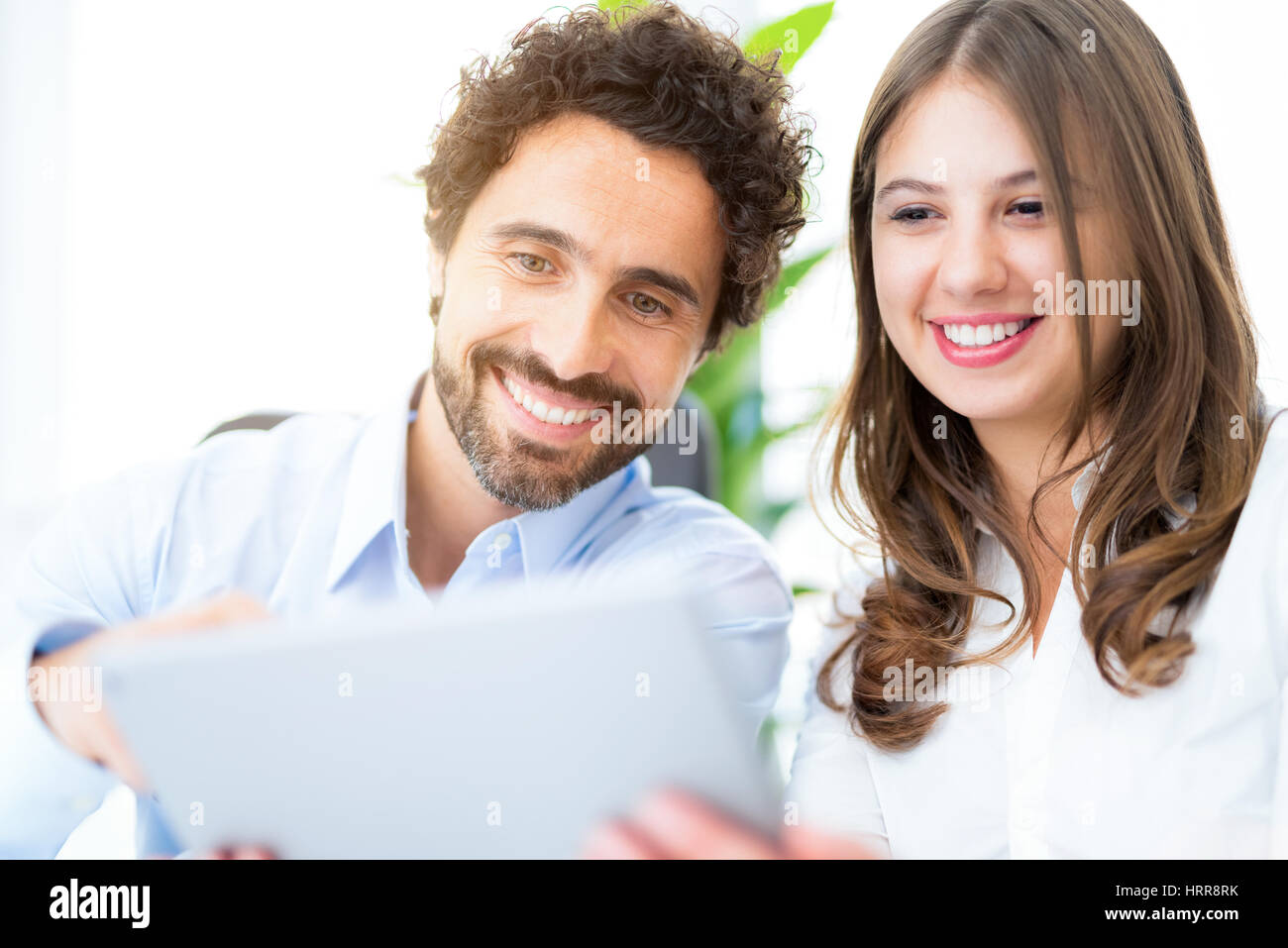 Smiling friendly people using a tablet Stock Photo - Alamy