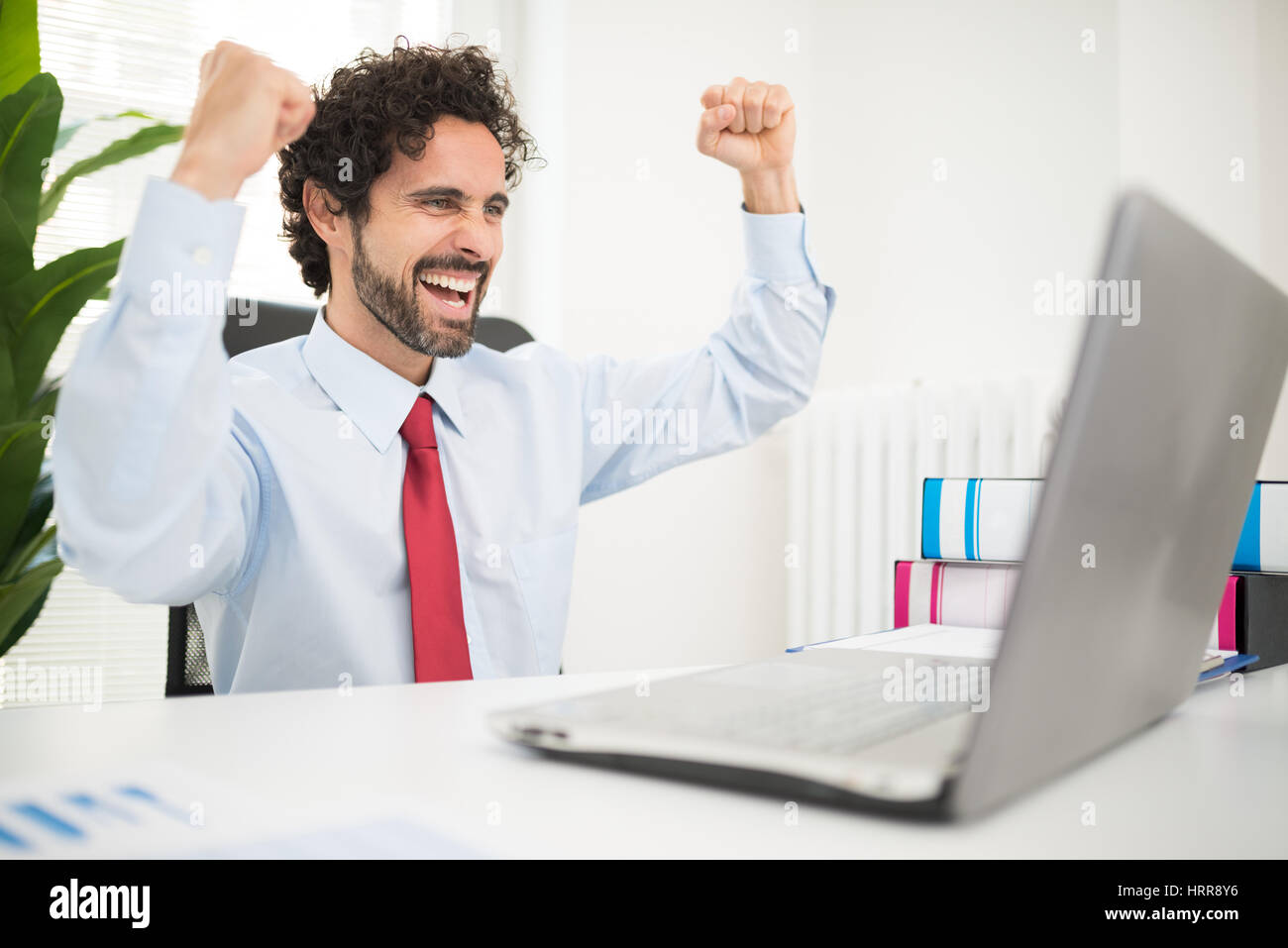 Very happy businessman looking at his computer Stock Photo - Alamy