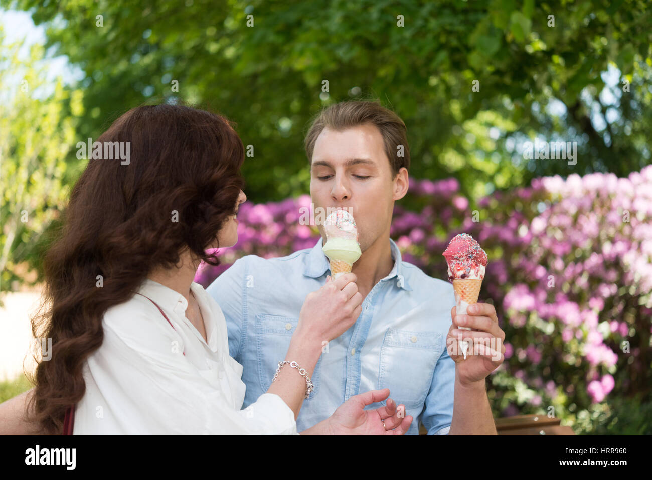 Happy couple eating an ice cream in a park Stock Photo - Alamy
