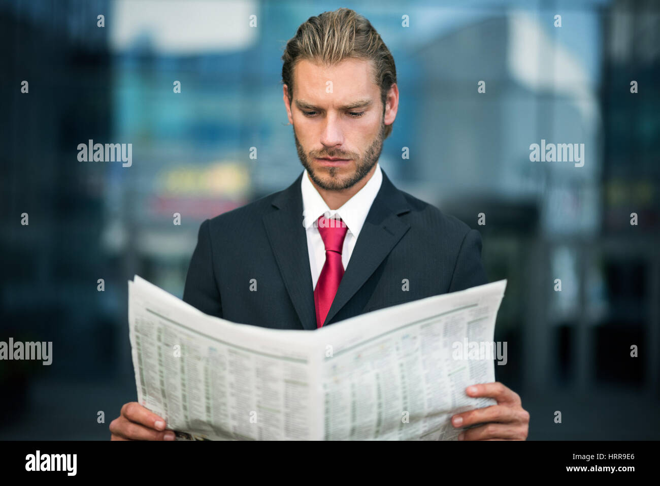 Handsome man reading a newspaper Stock Photo - Alamy