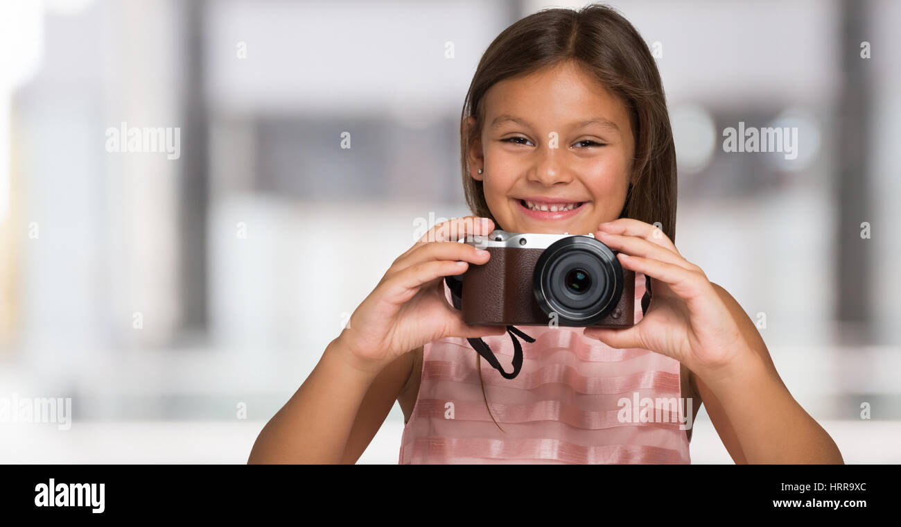 Smiling child holding a compact camera. Wide image, bright background ...