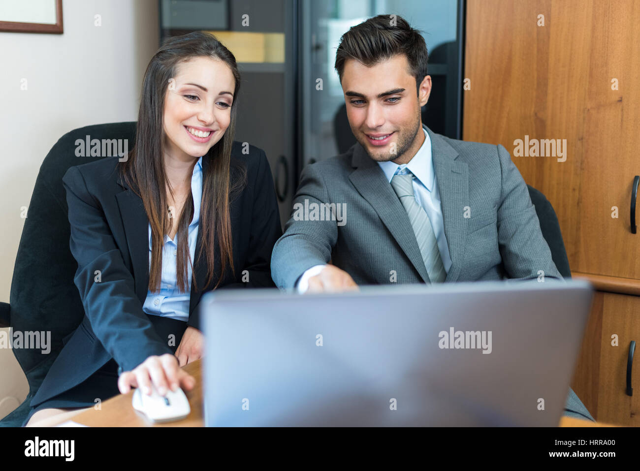 Smiling business people using a laptop computer in their office Stock ...