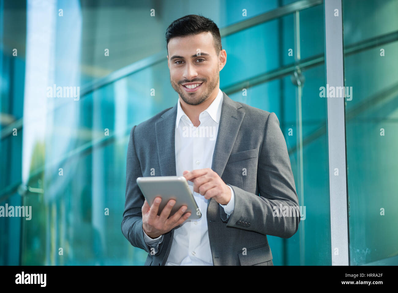 Business man using his digital tablet near a glass wall Stock Photo - Alamy