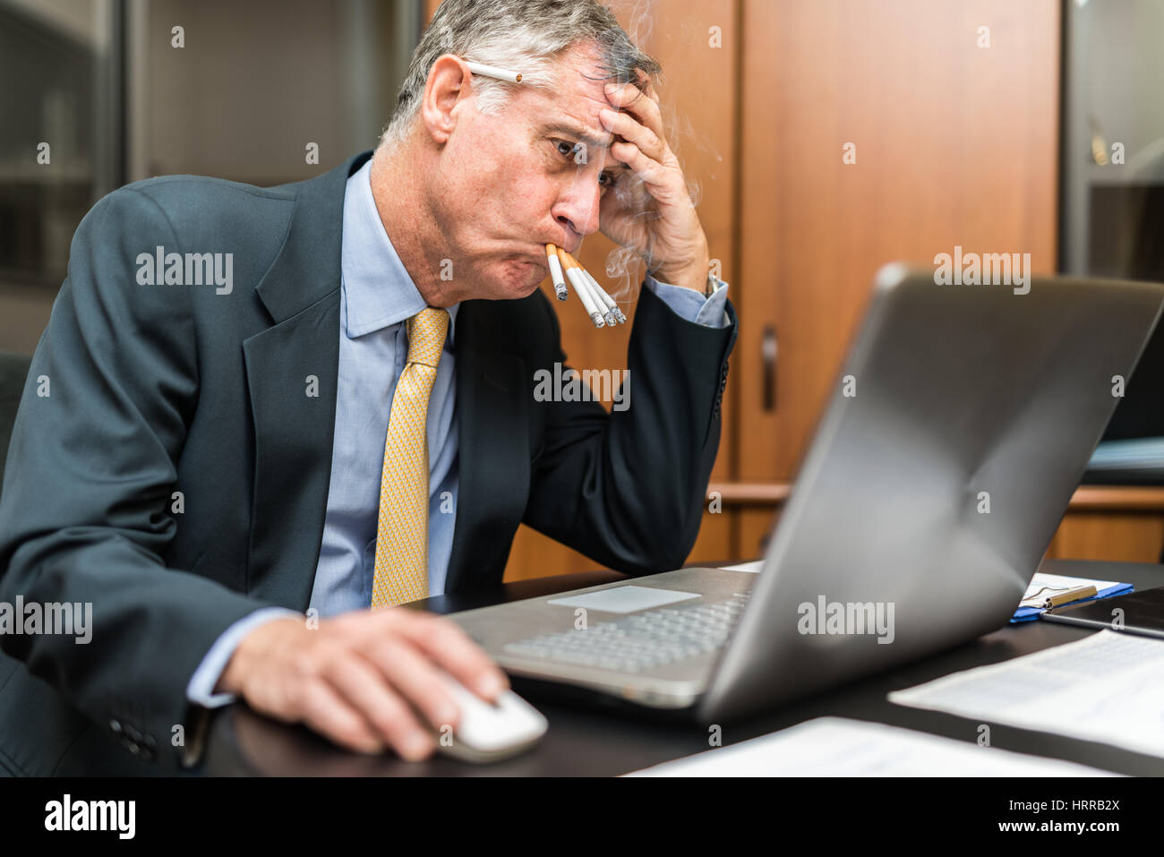Nervous businessman smoking a lot of cigarettes at once while looking ...