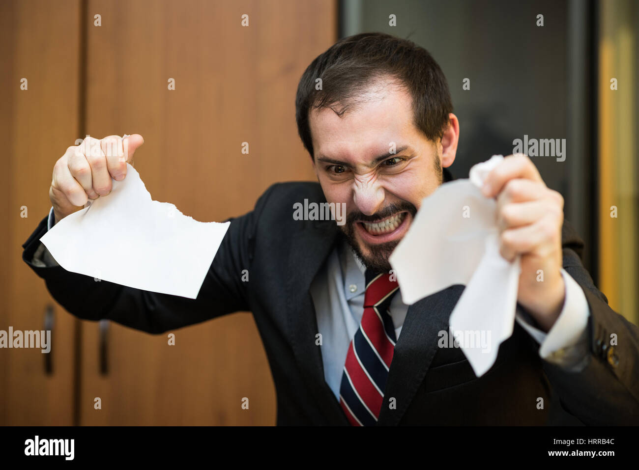 Angry businessman tearing apart a document in his office Stock Photo ...