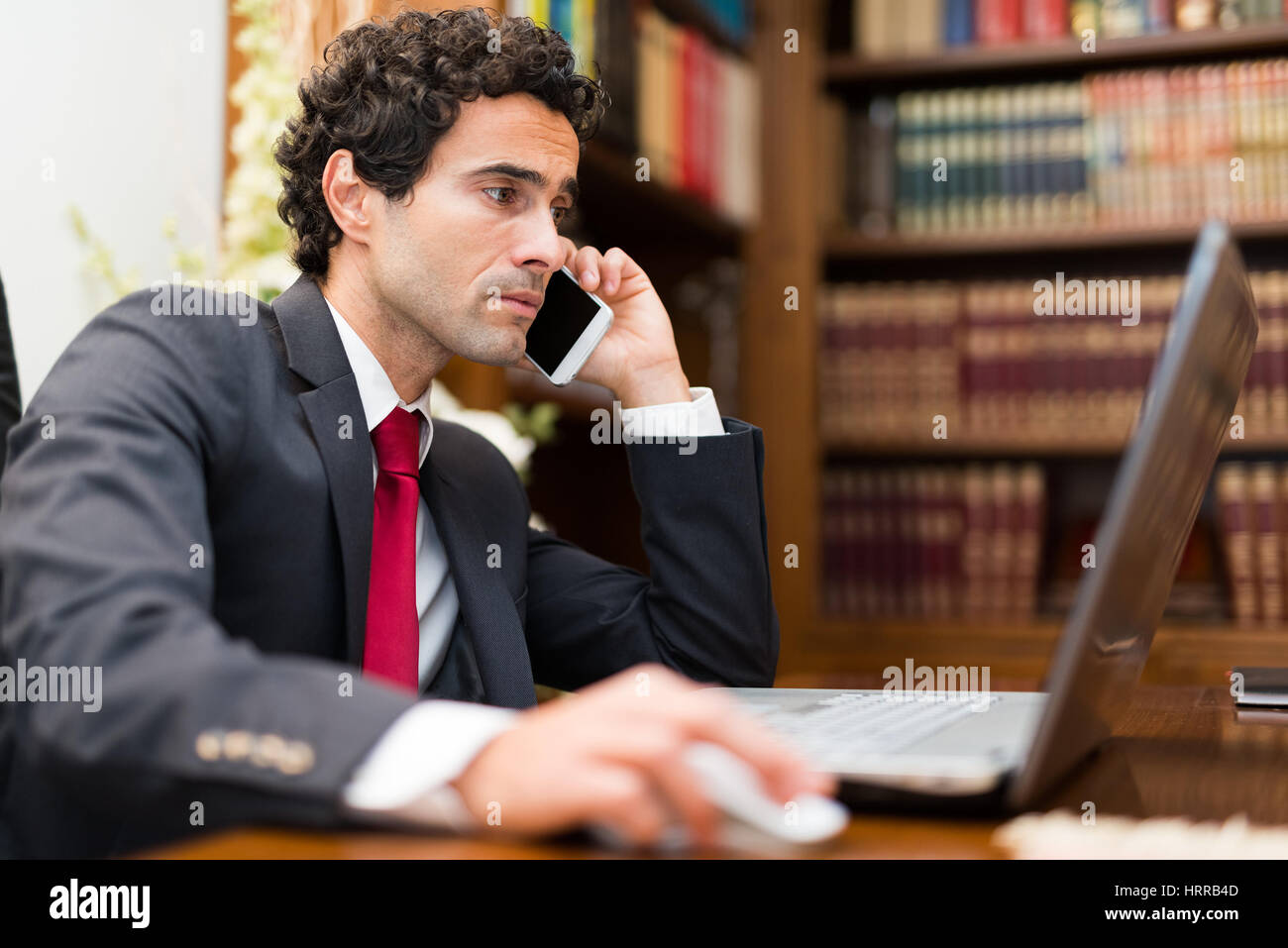 Man using his laptop computer while talking on the phone Stock Photo ...