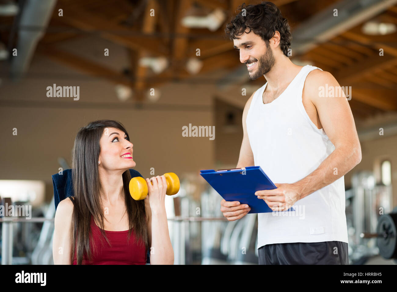 Woman working out in a gym while her personal trainer watches her ...