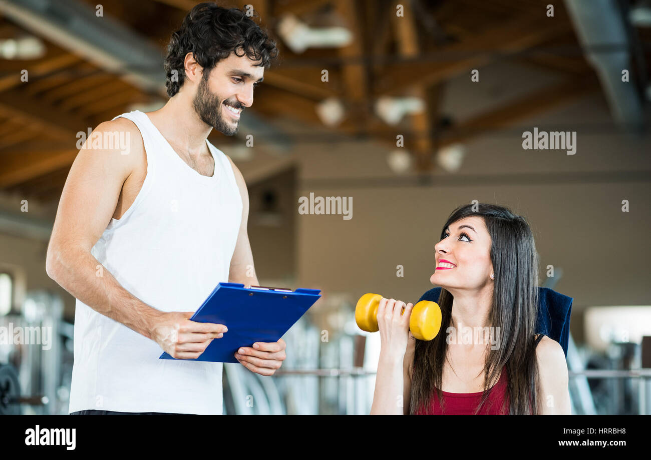 Personal trainer talking to a woman in a gym Stock Photo - Alamy