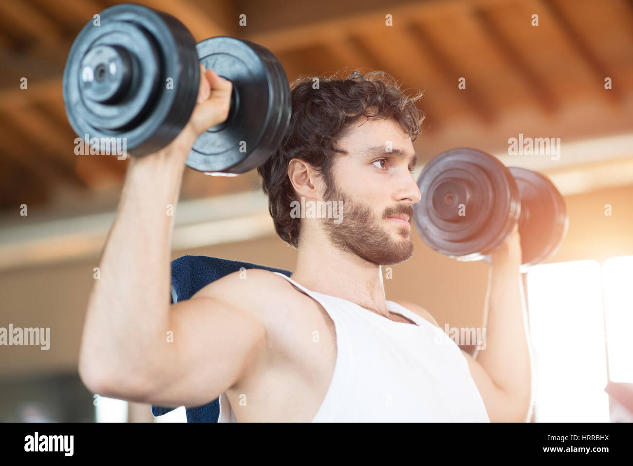 Man working out in a gym. Bright lens flare Stock Photo - Alamy