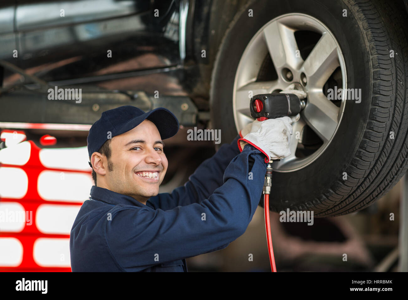 Portrait of a mechanic replacing a wheel Stock Photo - Alamy