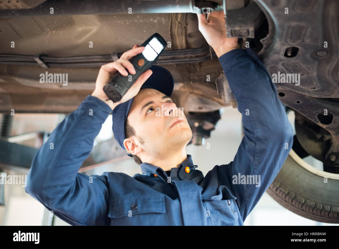 Mechanic inspecting a lifted car Stock Photo - Alamy