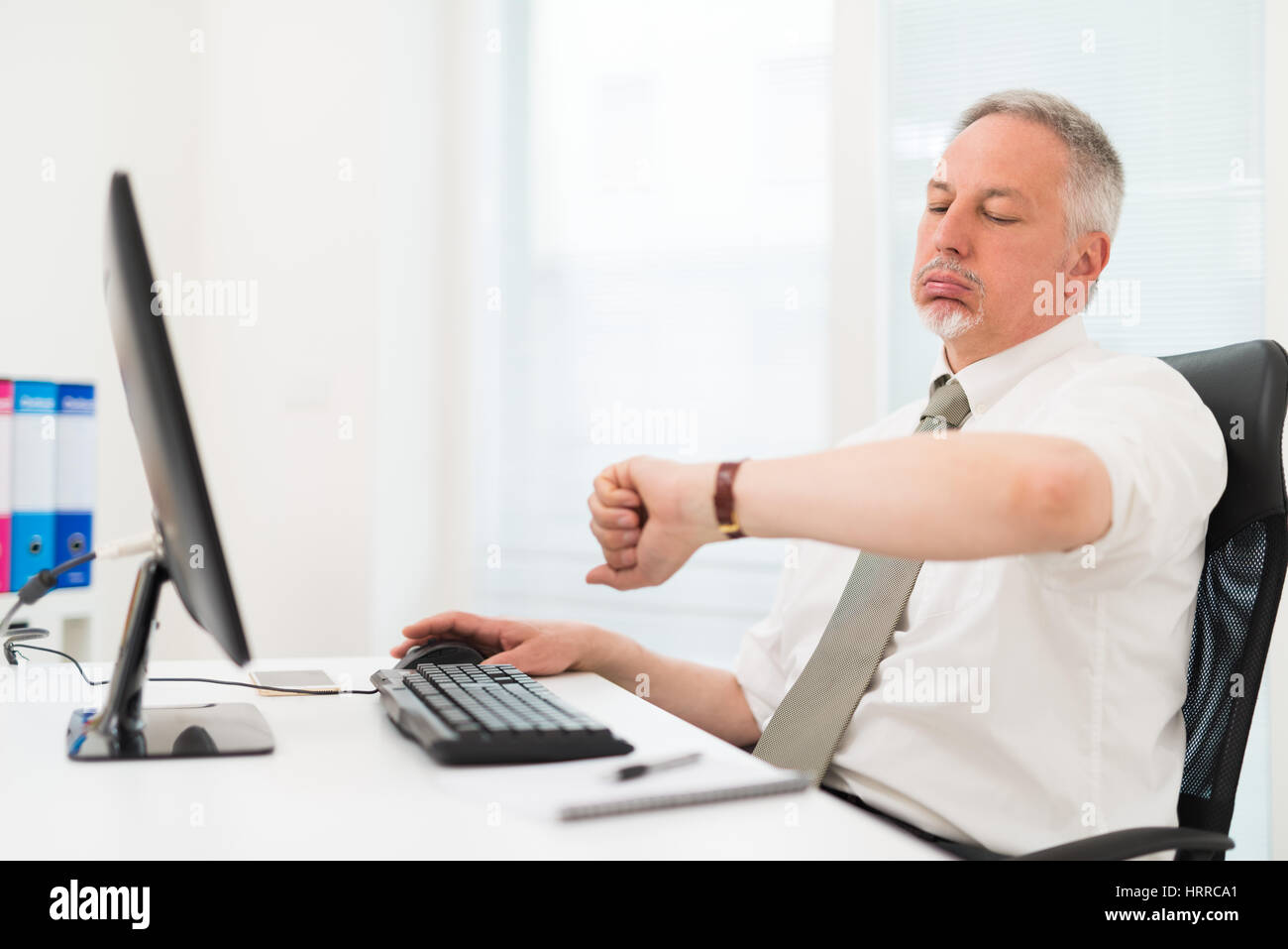 Bored businessman looking at his watch Stock Photo - Alamy