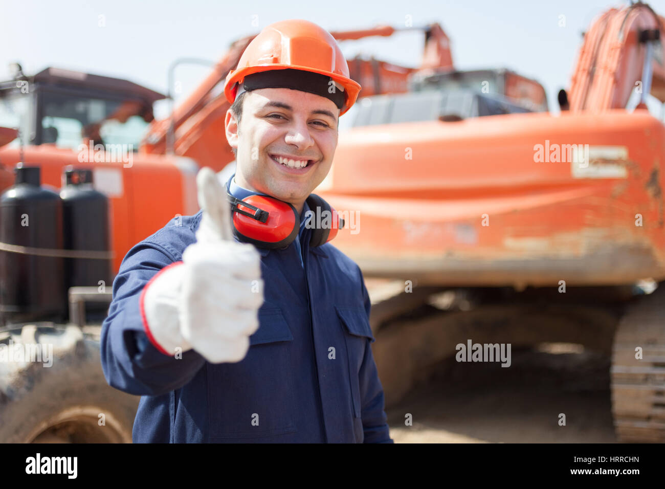 Happy worker in a construction site giving thumbs up Stock Photo - Alamy
